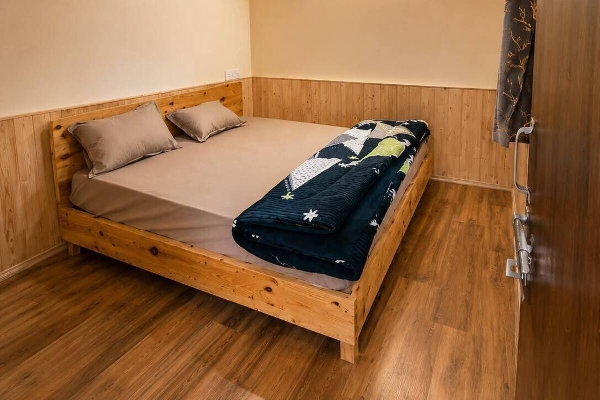 Uma cama de solteiro com estrutura de madeira e colcha, teto de madeira e piso de madeira.