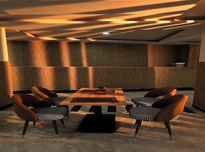 Uma sala de conferência moderna com uma mesa e cadeiras de madeira, teto com luminárias lineares e parede revestida em madeira.