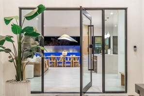 Um interior moderno com área de refeições, uma planta grande em vaso e um lustre contemporâneo.