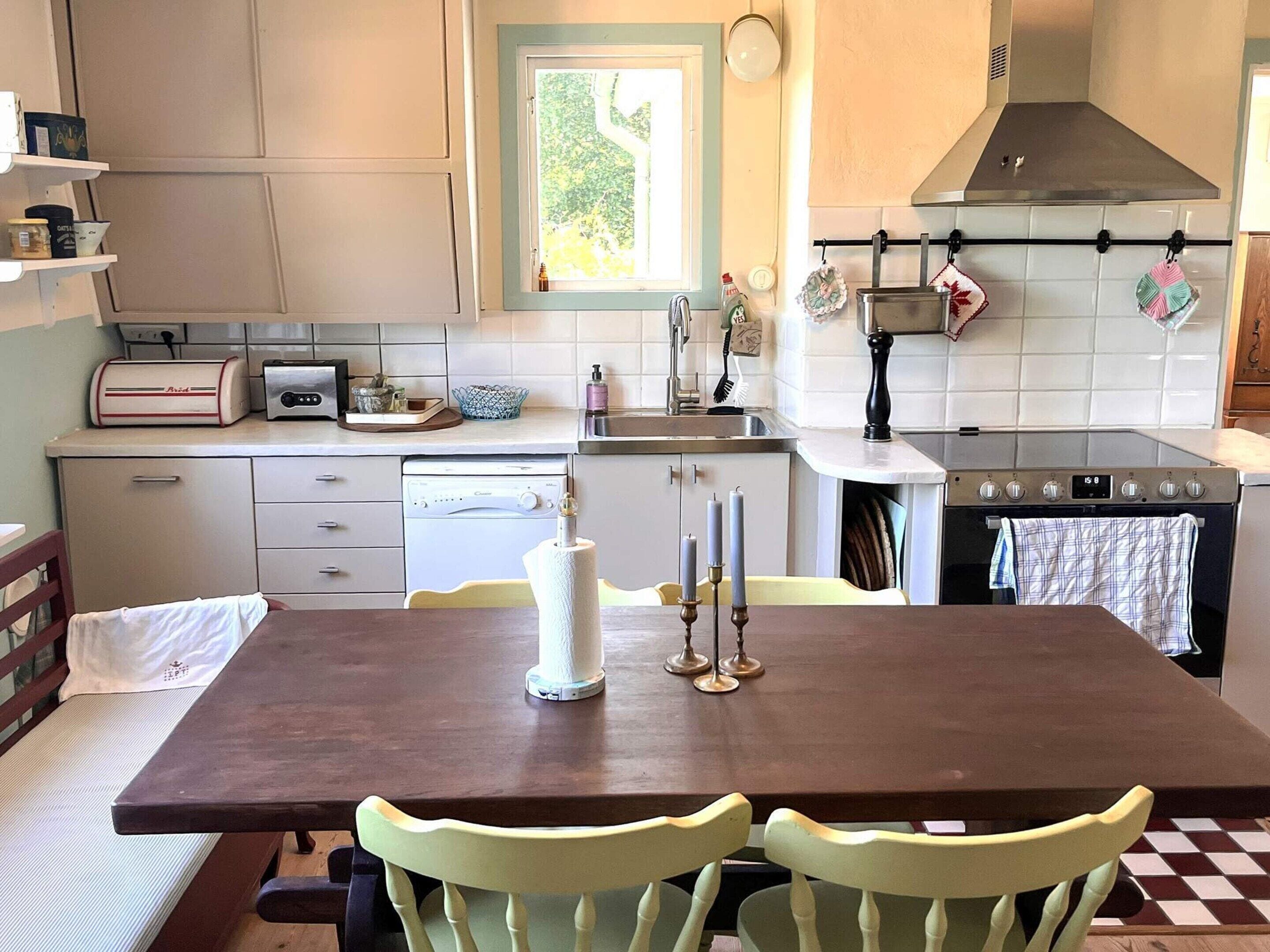 Uma cozinha com uma mesa de madeira, duas cadeiras, um fogão e uma janela.