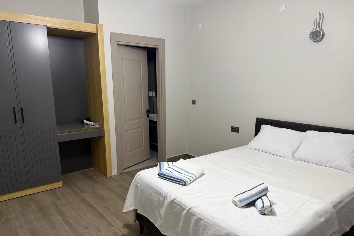 Quarto de hotel com uma cama, um guarda-roupa e uma porta que dá para um banheiro.