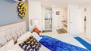 Quarto de hotel com uma cama, luminária de cabeceira, chuveiro e banheiro.