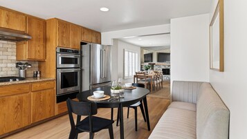 Uma cozinha moderna com armários de madeira, eletrodomésticos de aço inoxidável e uma área de refeições com uma mesa redonda e cadeiras.