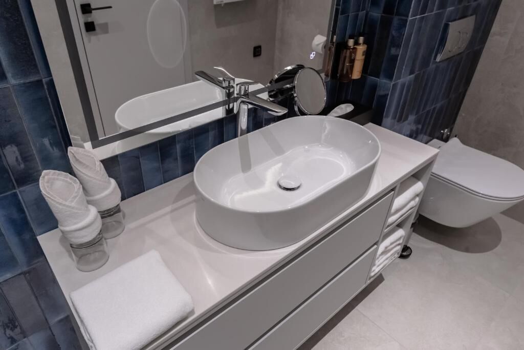 Um banheiro moderno com uma pia oval grande, um espelho, um vaso sanitário e um porta-toalhas.