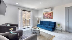 Uma sala de estar moderna com um sofá, uma mesa de centro e um quadro na parede.