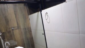 Uma casa de banho com chuveiro, sanita e lavatório.