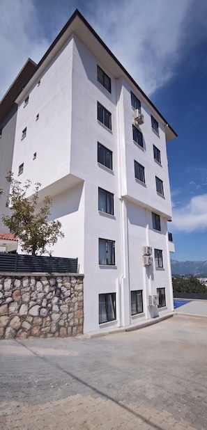 Um edifício de vários andares com fachada branca, diversas janelas e aparelhos de ar condicionado.