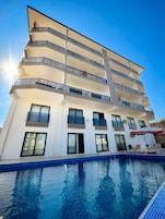 Um hotel com vários andares, piscina e área de estar externa.