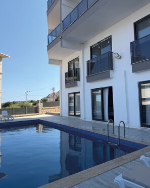 Um edifício moderno com piscina, varandas e céu claro.