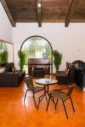 Um quarto com lareira, uma mesa redonda com cadeiras e uma grande janela em arco.