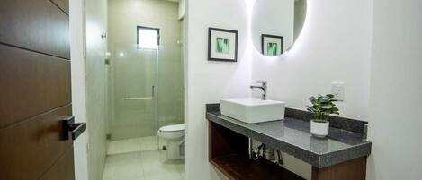 Casa de banho moderna com lavatório branco, espelho e zona de duche.