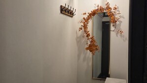 Um banheiro com espelho, porta-toalhas e uma planta decorativa.