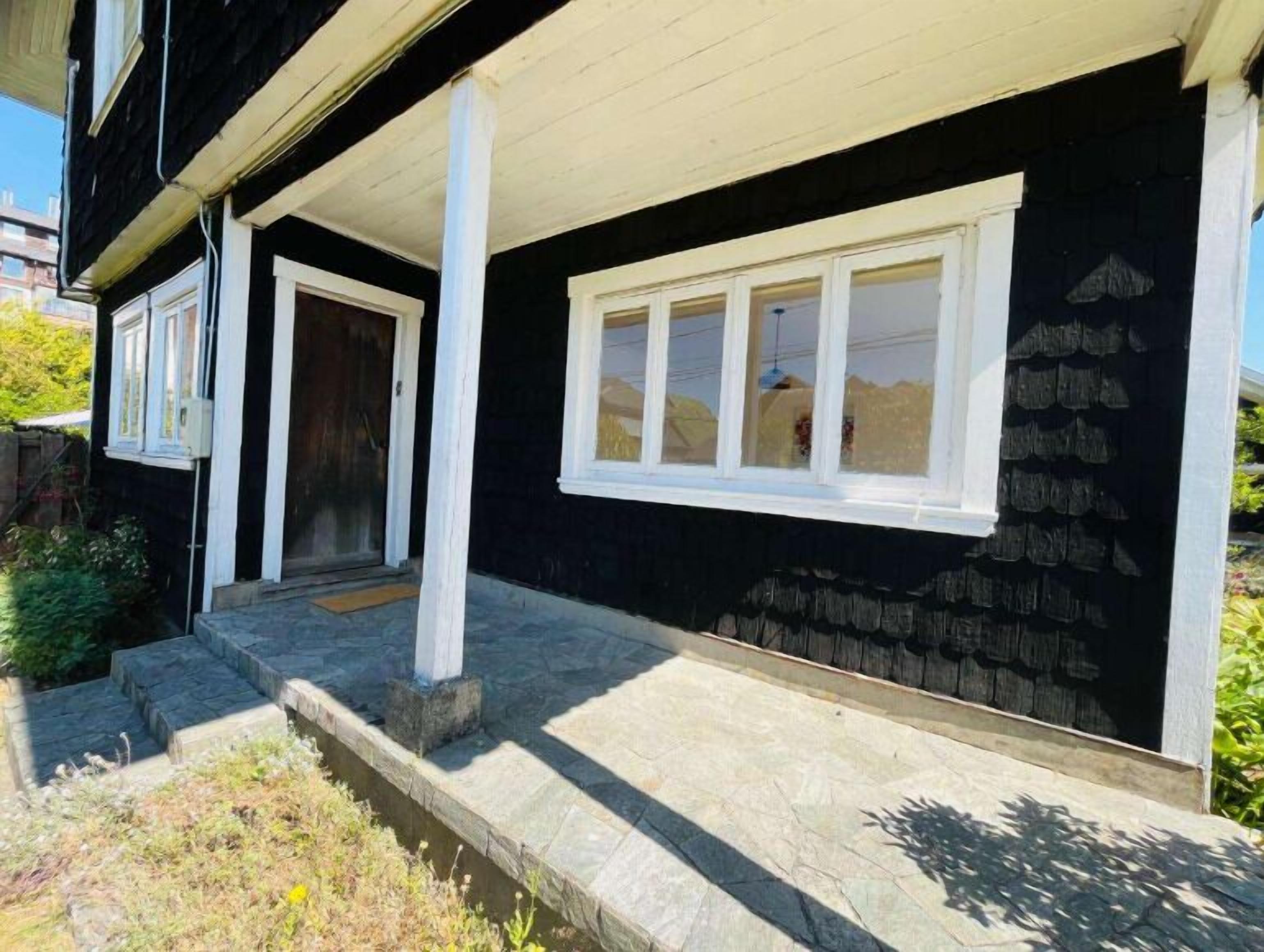 Um edifício preto com detalhes brancos, uma porta e uma janela.