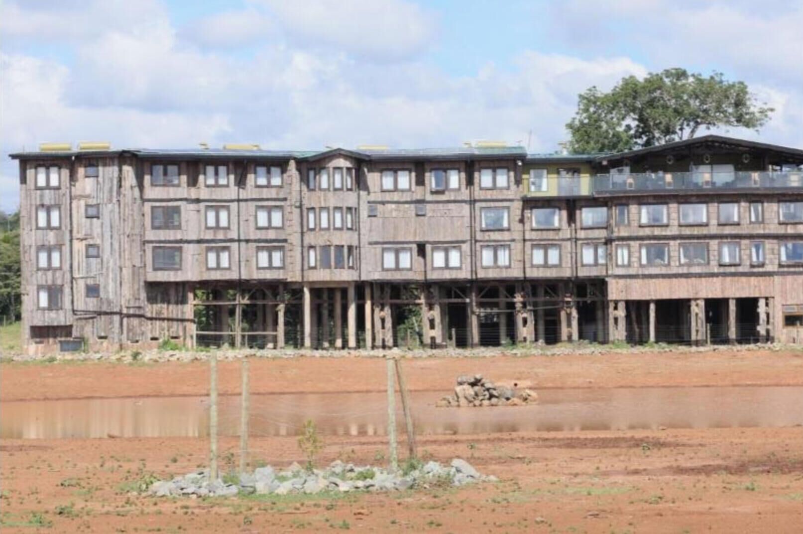 Um edifício de vários andares com várias janelas e varandas, situado em uma paisagem árida.
