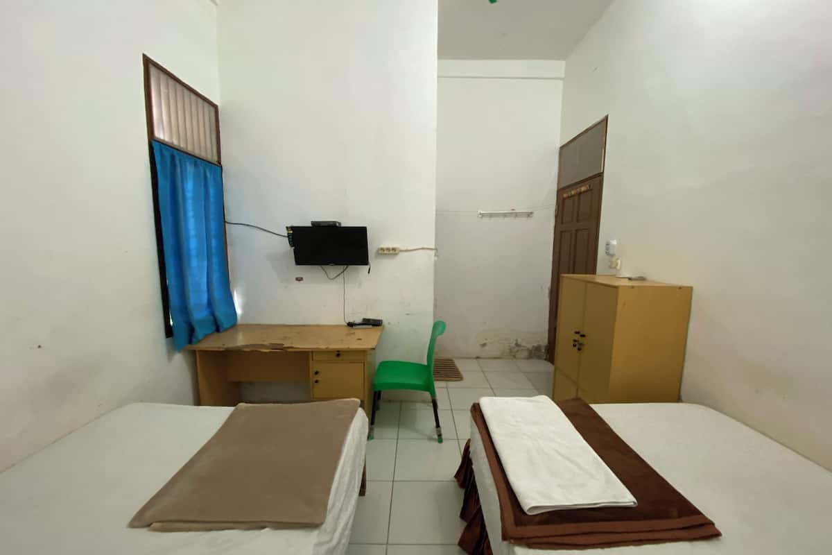 Quarto com duas camas, uma escrivaninha, uma cadeira, uma televisão e um guarda-roupa.
