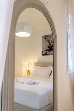 Quarto com cama, luminária e um quadro na parede.