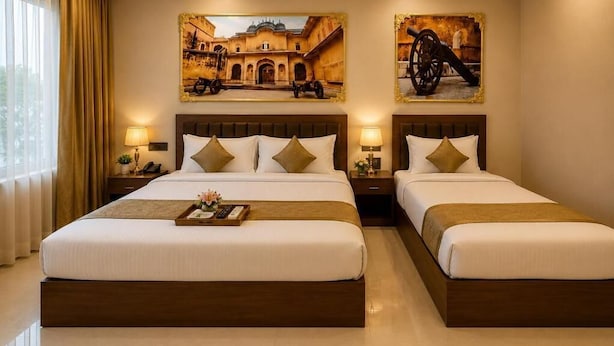 Quarto de hotel com duas camas, uma janela grande com cortinas e obras de arte nas paredes.