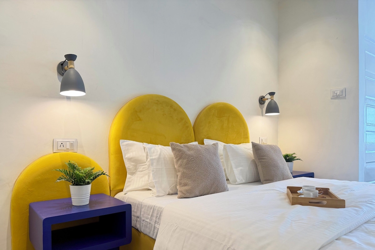 Quarto bem arrumado com cama, mesas de cabeceira e um vaso de planta.