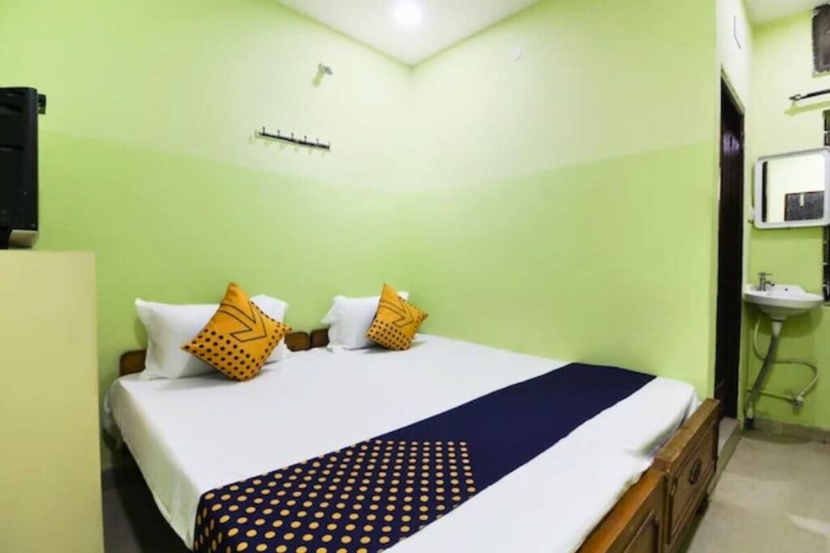 Quarto com cama, mesinha de cabeceira, ar-condicionado fixado na parede e janela.