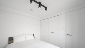 Um quarto com uma cama, um guarda-roupa e uma porta.