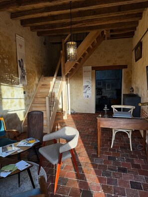 Um interior rústico com escada de madeira, mesa de jantar e uma cadeira.