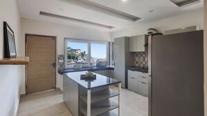 Uma cozinha moderna com ilha central, forno embutido e uma grande janela com vista para a cidade.