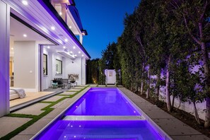 Uma casa moderna com piscina, área de estar externa e um pátio bem iluminado.
