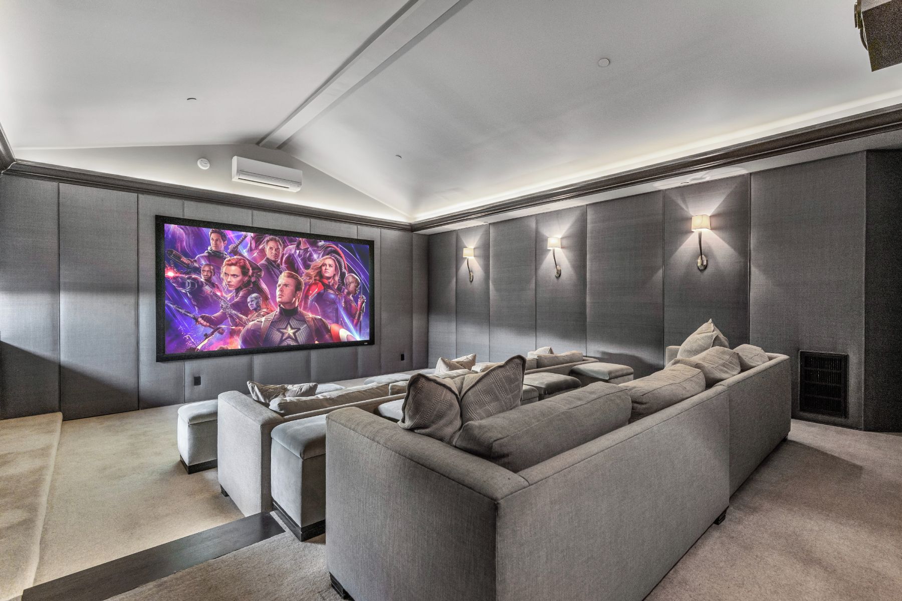 Uma sala de cinema moderna com uma grande TV de tela plana, assentos confortáveis e iluminação ambiente.