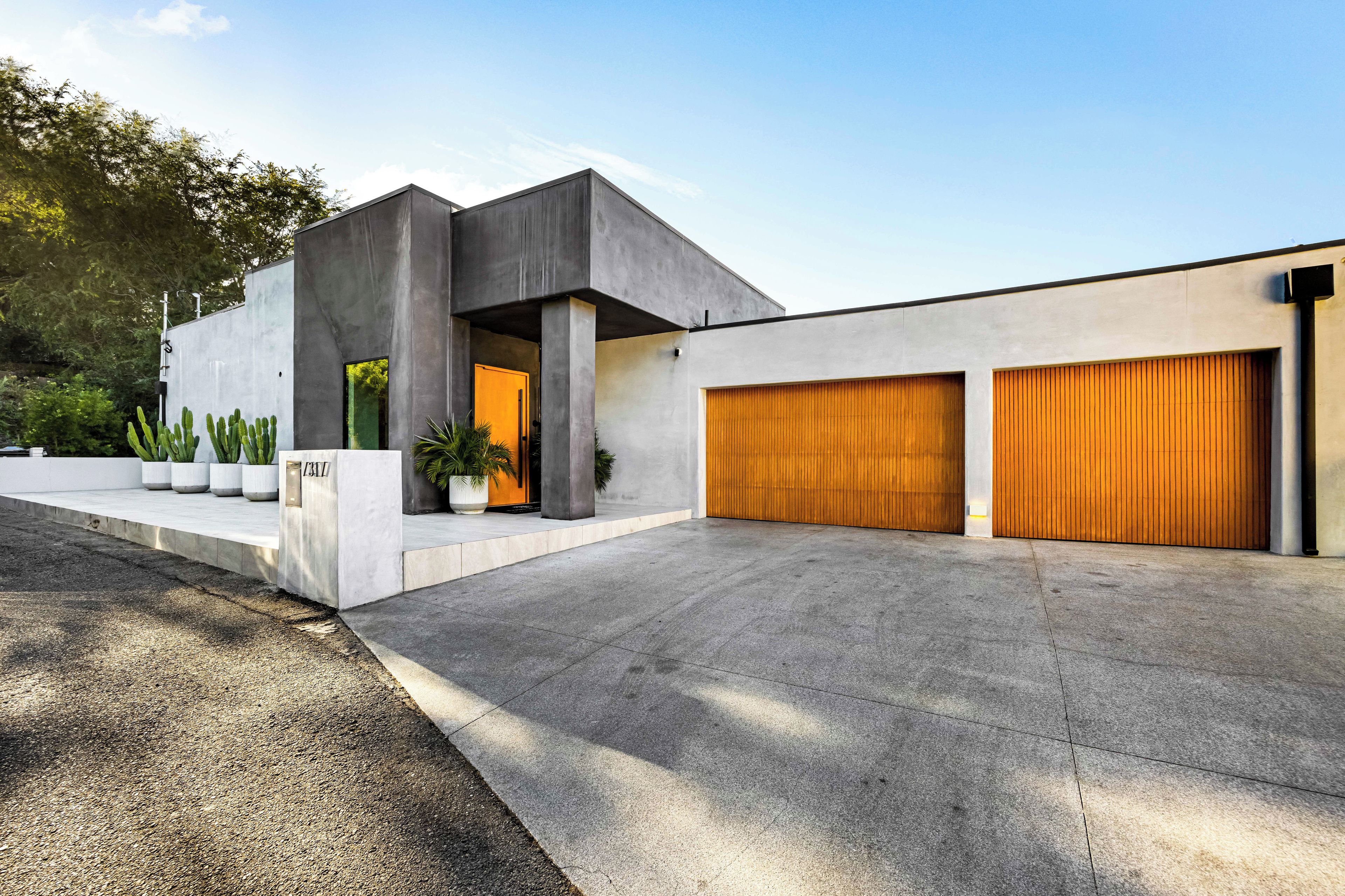 Uma casa moderna de dois andares, com fachada de concreto, entrada por automóvel e duas garagens.