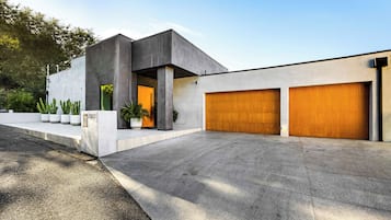 Uma casa moderna de dois andares, com fachada de concreto, entrada por automóvel e duas garagens.