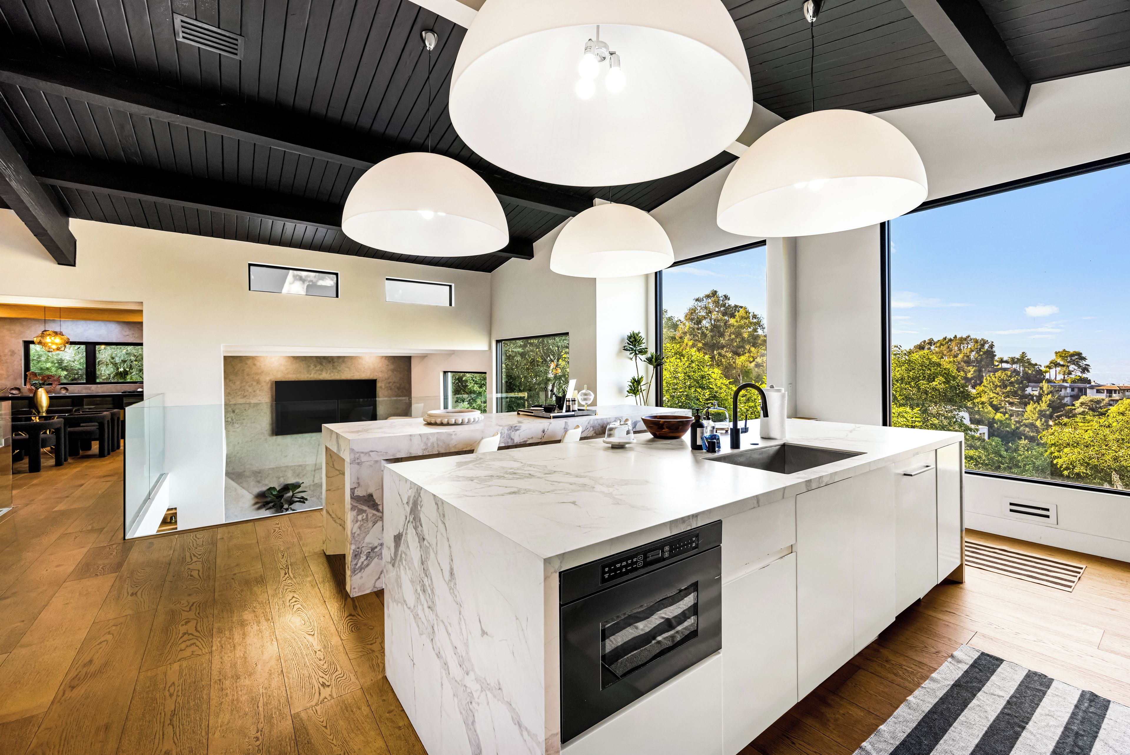 Cozinha moderna com ilha grande, eletrodomésticos embutidos e vista para o exterior.