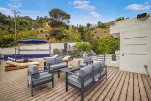 Um terraço no telhado com área de estar externa, piscina e vista para uma encosta.