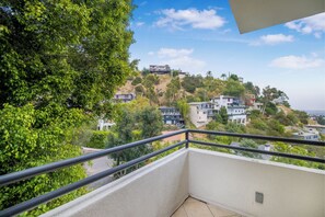 Uma varanda com vista para casas e vegetação numa encosta.