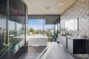 Um banheiro moderno com chuveiro em cabine de vidro, uma banheira separada e uma grande janela com vista para a cidade.