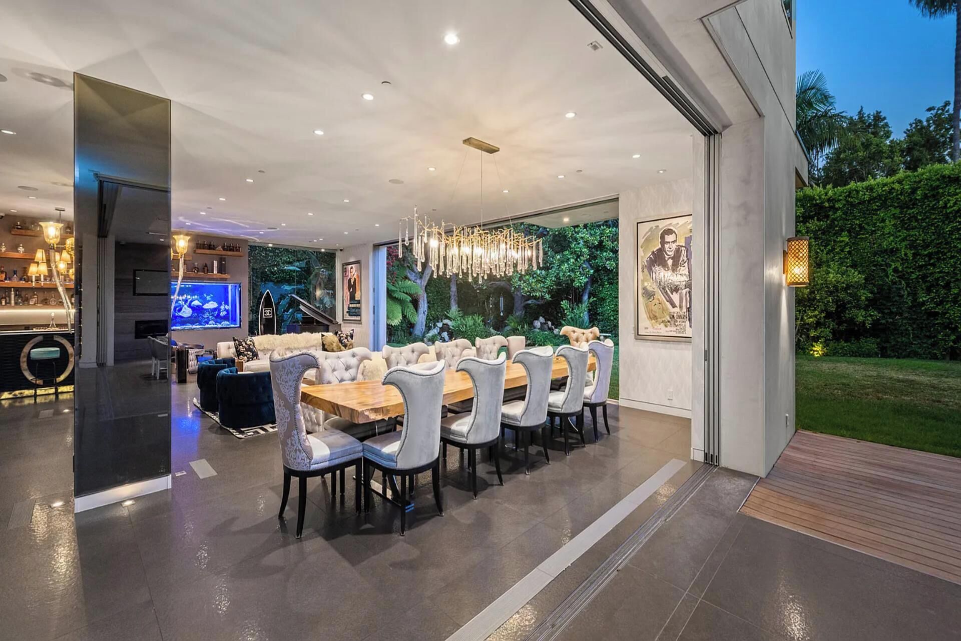 Uma sala de jantar moderna com uma mesa comprida e cadeiras, um espaço de bar com um piano e um grande aquário.
