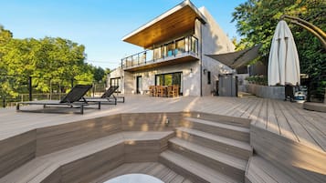 Uma casa moderna com um deck, área de estar externa e lareira.