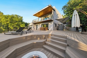 Uma casa moderna com um deck, área de estar externa e lareira.