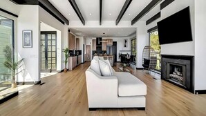 Uma sala de estar ampla com um sofá branco, piso de madeira e uma lareira.