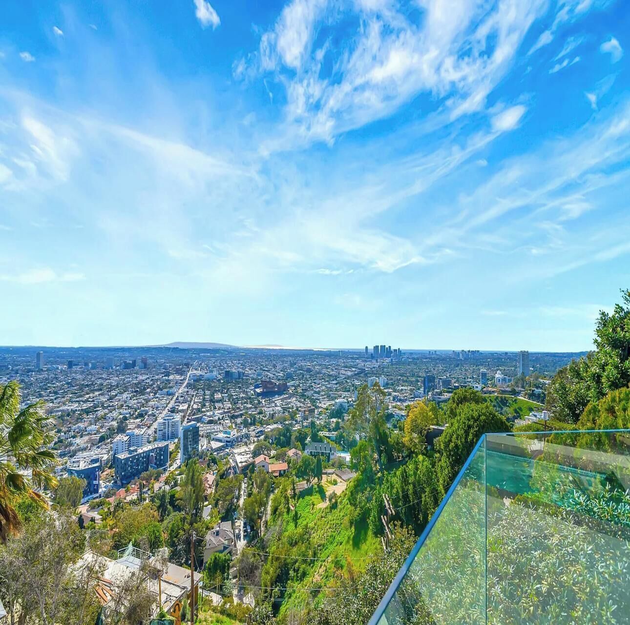 Vista panorâmica de uma paisagem urbana com céu claro, área urbana densa e áreas verdes.