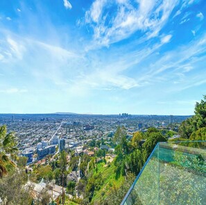 Vista panorâmica de uma paisagem urbana com céu claro, área urbana densa e áreas verdes.