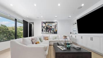 Uma sala de estar moderna com um sofá modular, uma mesa de centro e uma televisão de tela grande.