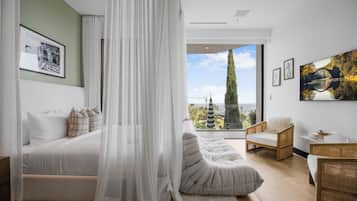 Quarto com cama, janela ampla, cadeira e vista para o exterior.