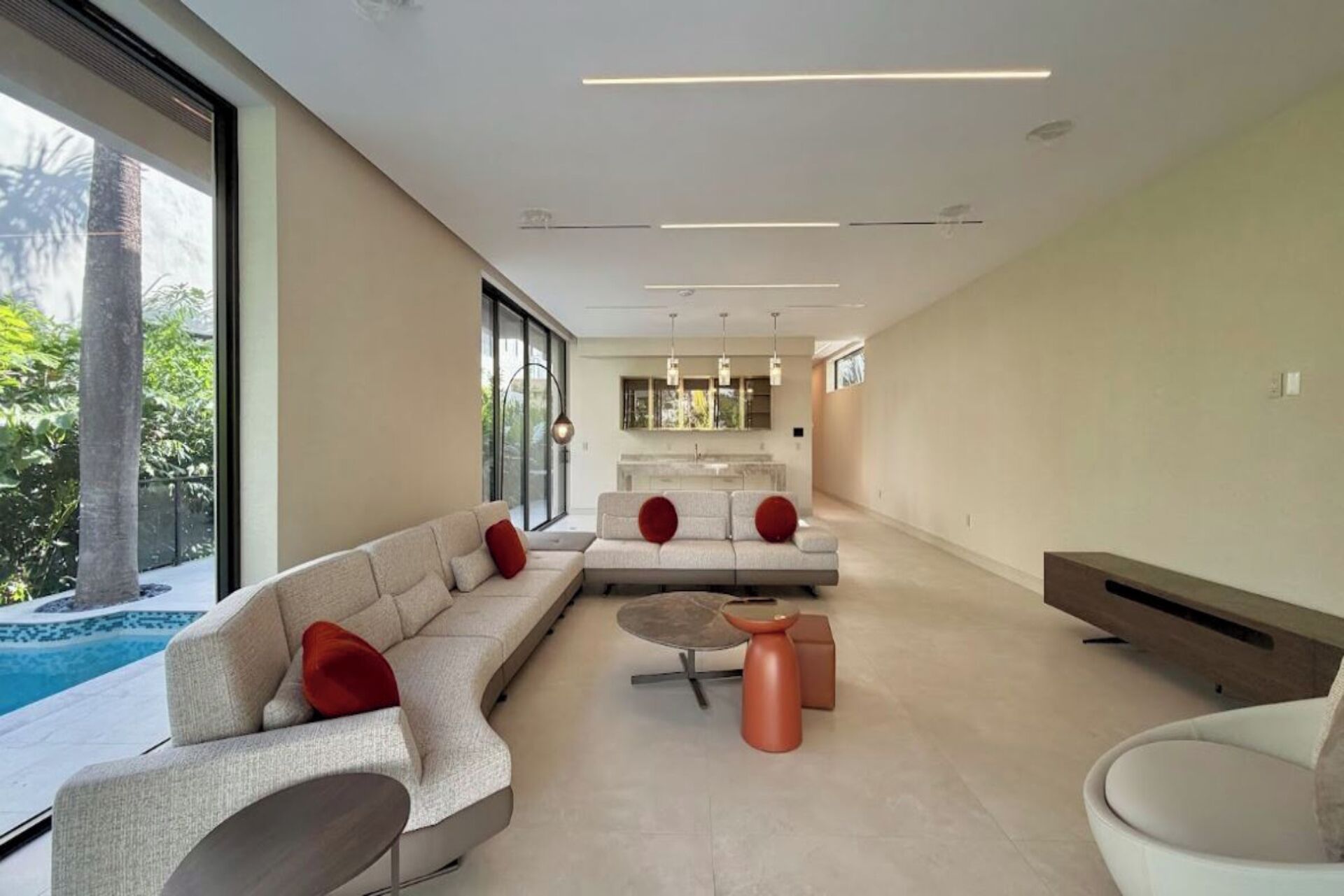Uma sala de estar moderna com sofá, mesa de centro e vista para uma piscina.