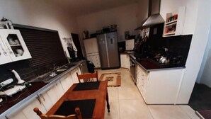 Uma cozinha compacta com uma mesa de jantar, cadeiras, geladeira e fogão.