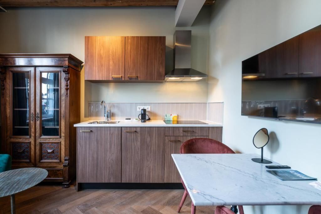 Uma cozinha moderna com armários de madeira, bancada de mármore e uma área de refeições com mesa e cadeiras.