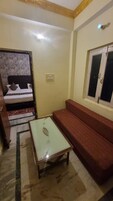 Quarto com cama, sofá, mesinha, janela e interruptor na parede.