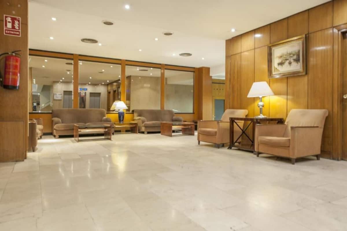 Um saguão de hotel com balcão de recepção, área de estar e extintor de incêndio.