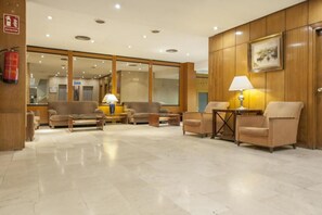 Um saguão de hotel com balcão de recepção, área de estar e extintor de incêndio.