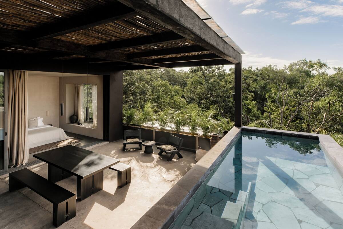 Uma área de estar moderna ao ar livre, com piscina, assentos e vista para o verde circundante.