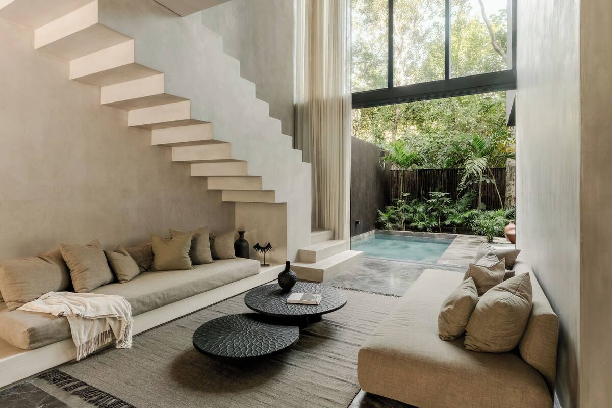 Uma sala de estar moderna com escada, piscina e vista para o verde.